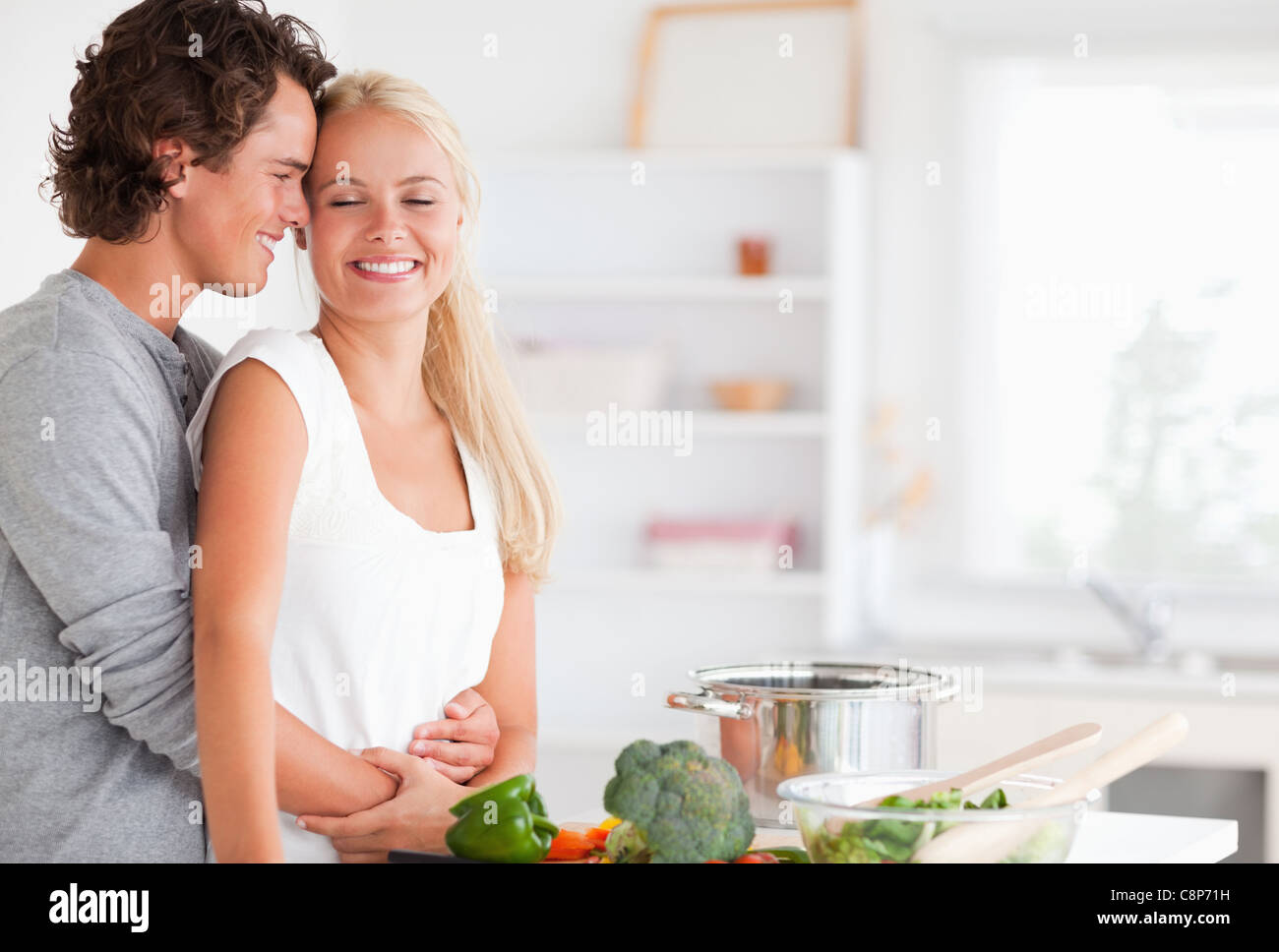 Beautiful couple hugging while cooking Stock Photo - Alamy