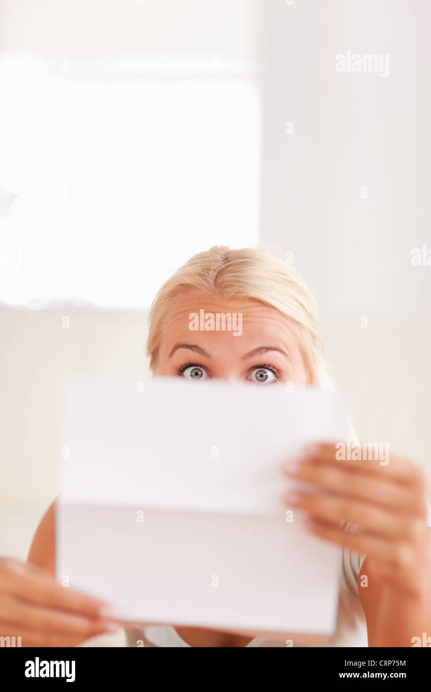 Shocked blond woman reading a letter Stock Photo - Alamy