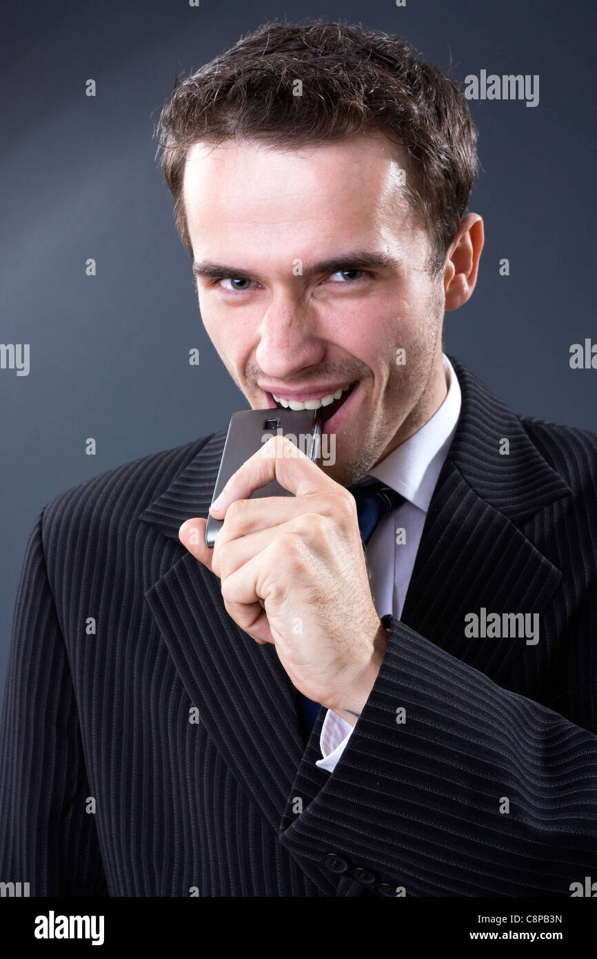 handsome businessman biting mobile phone made in studio Stock Photo - Alamy