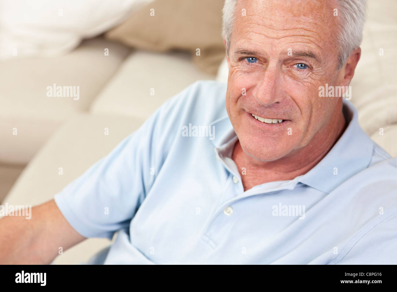 Happy and healthy senior man sitting on a sofa at home smiling and ...