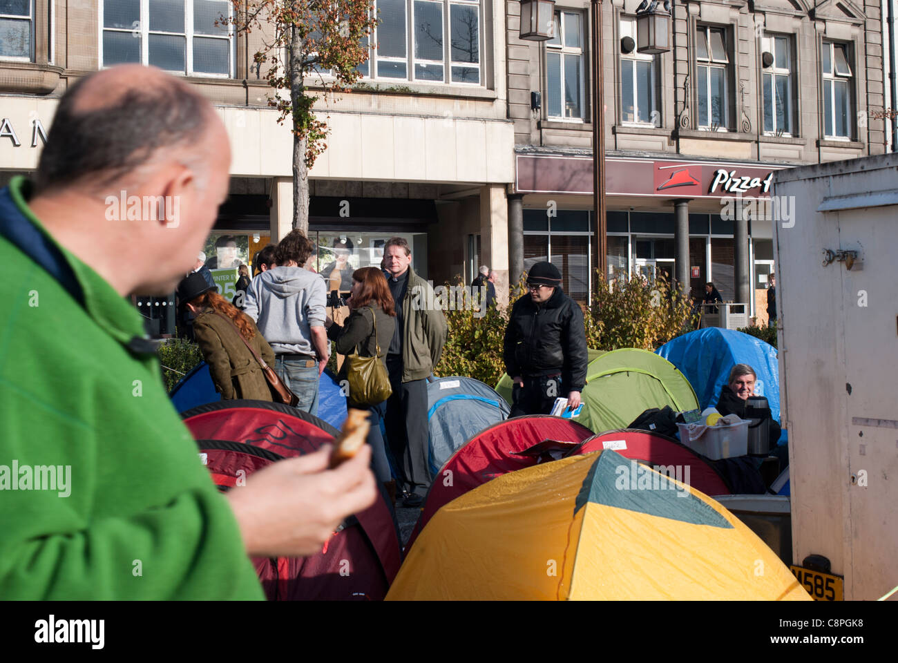 Man eating whilst walking by the protesters camp of the Occupy Movement ...