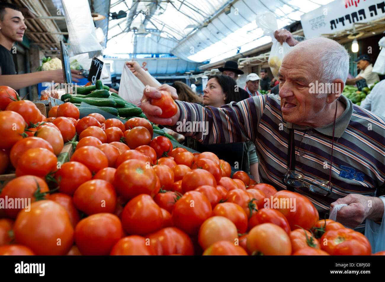 An old man choosing tomatoes from a big tomato stand in the Machne ...