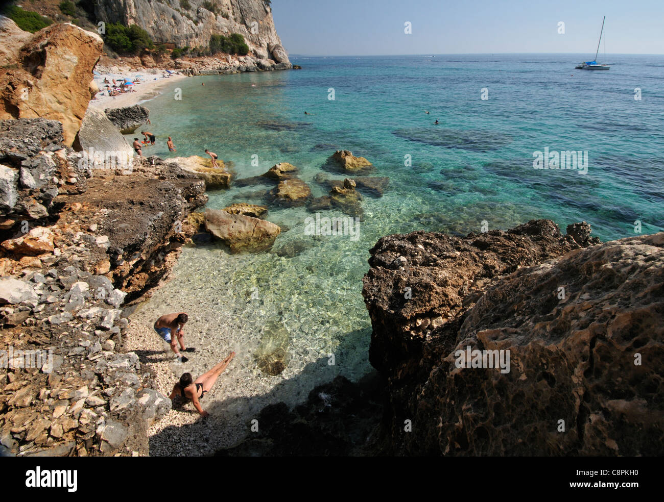People enjoy the beach and transparent waters at Cala Fuili, Cala ...