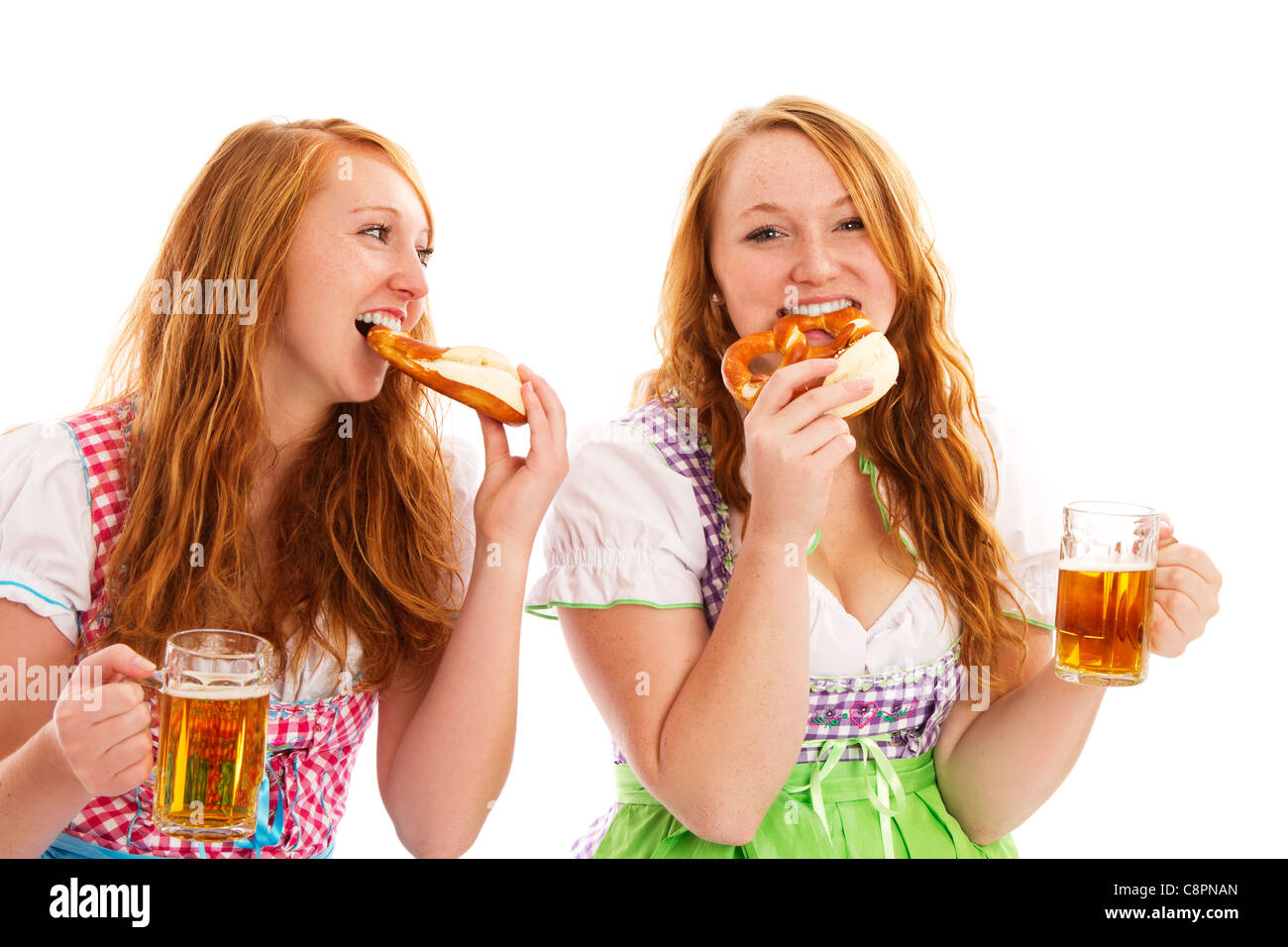 two bavarian women eating pretzels and holding beer on white background ...