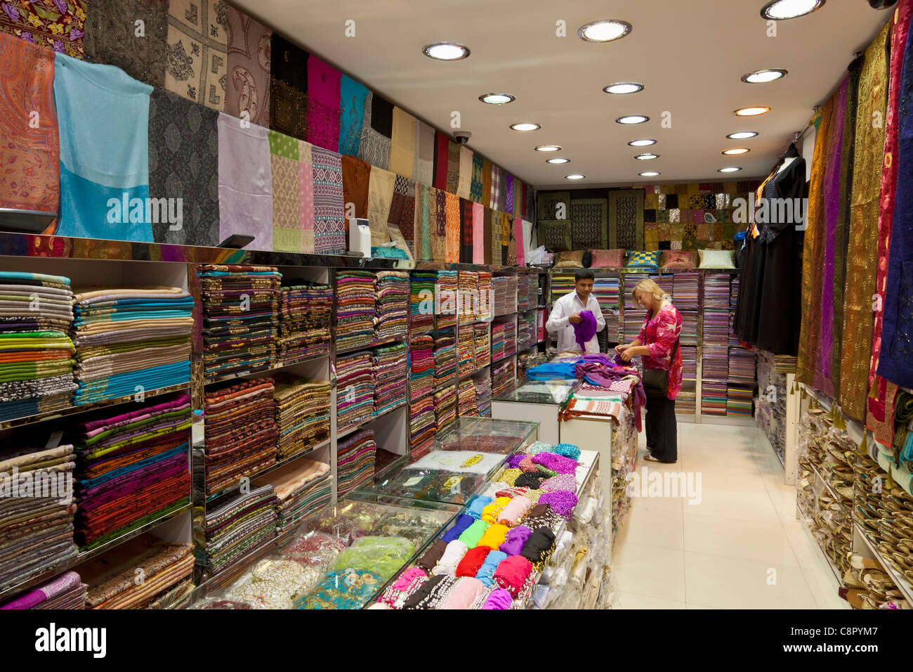 Tourist woman (MR) buying a scarf or pashmina in the Dubai textile souk ...