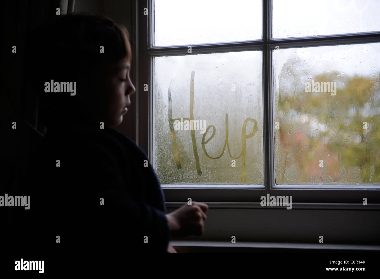 6 year old boy writing 'help 'on the window Stock Photo - Alamy