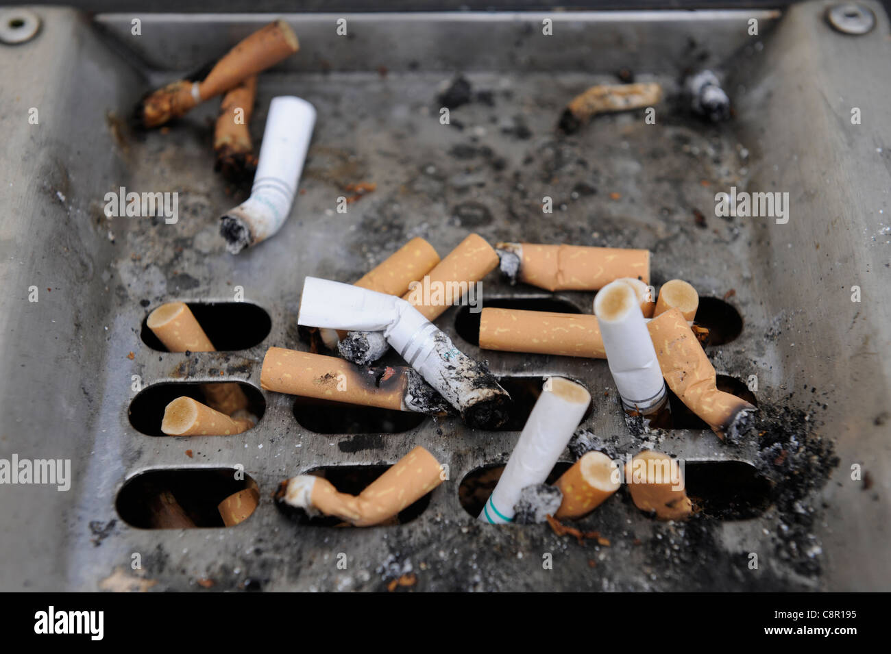 cigarette ends in an ouside ashtray uk Stock Photo - Alamy