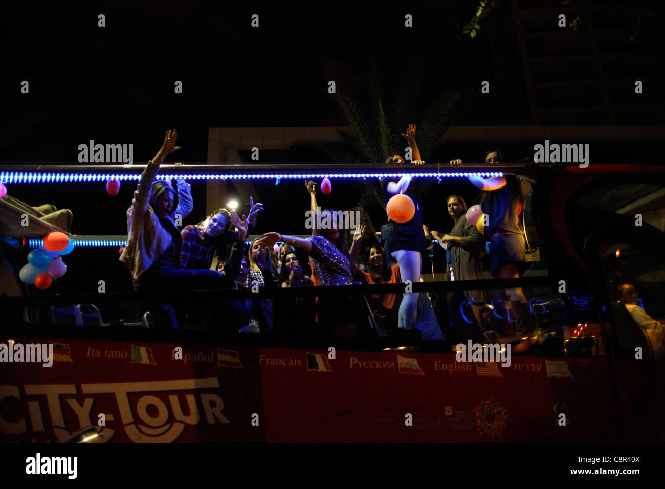 Youngsters in a two deck City Tour bus at night downtown Tel Aviv ...