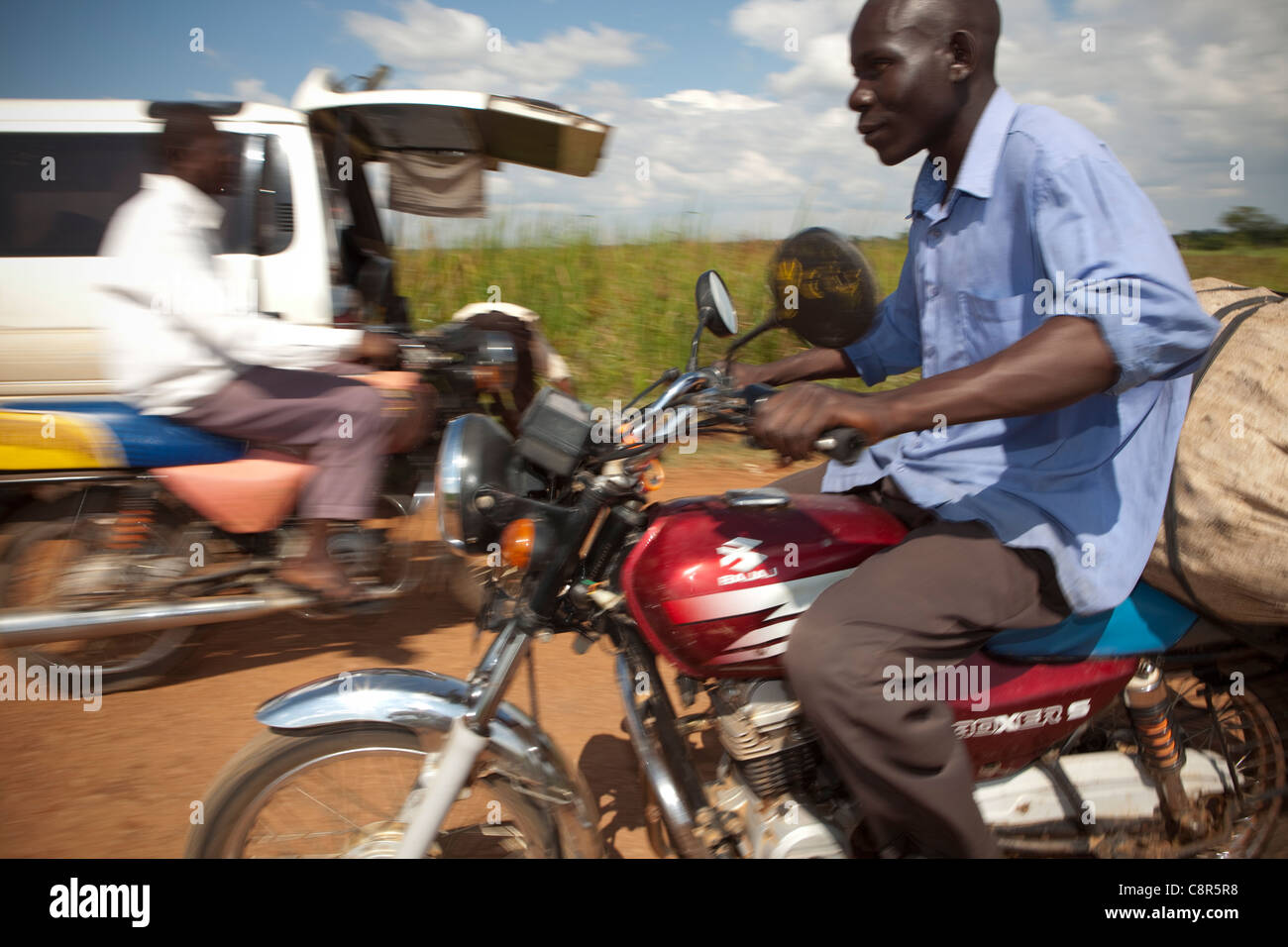 Motorists ride along a dirt road in Pallisa District in Eastern Uganda ...