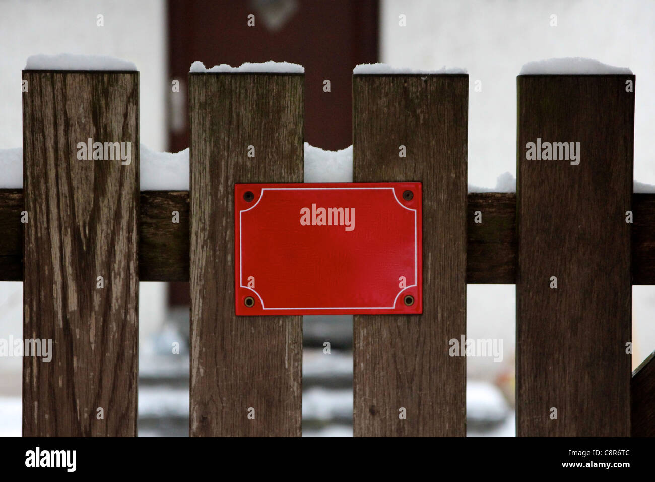 A small empty red sign mounted on a fence or gate of wooden planks ...