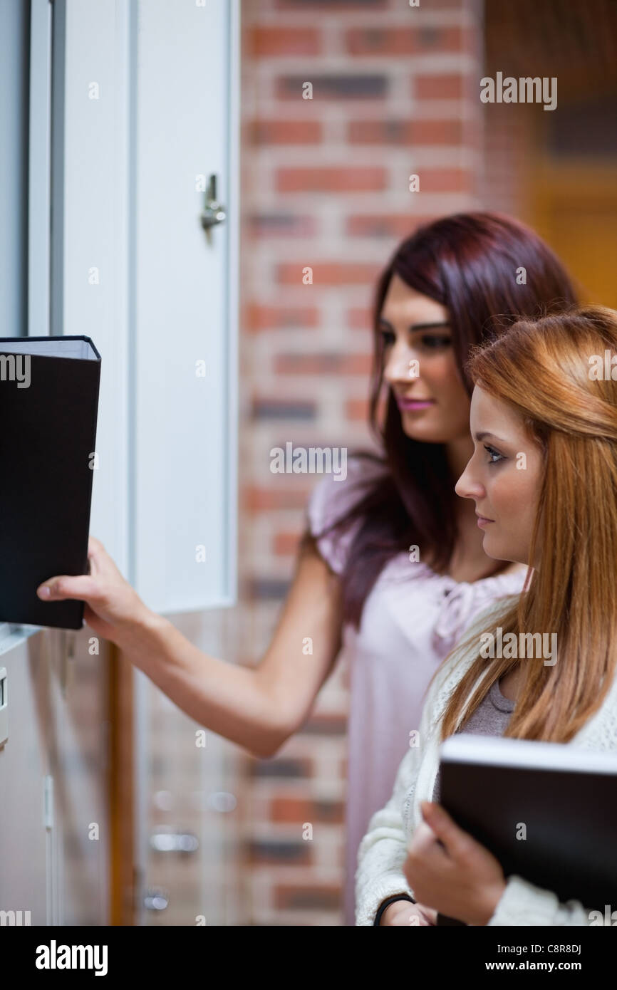 Portrait of a student putting her binder in a locker Stock Photo - Alamy