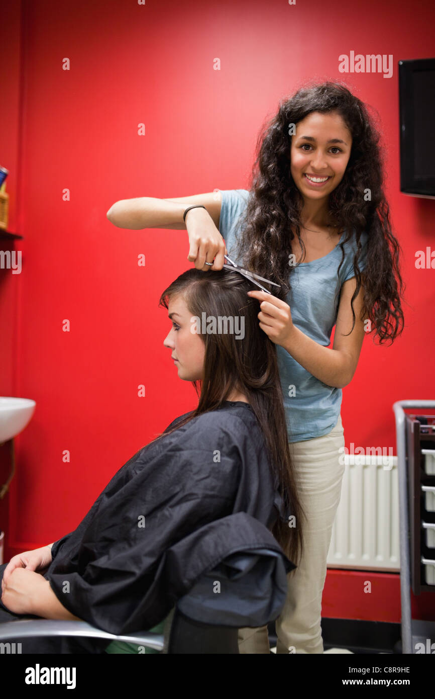 Portrait of a happy female hairdresser cutting hair Stock Photo - Alamy