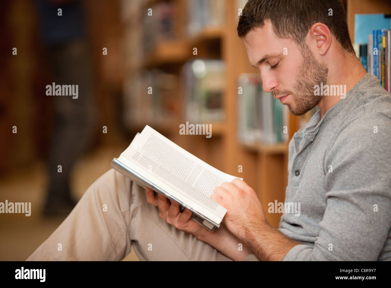 Serious male student reading a book Stock Photo - Alamy