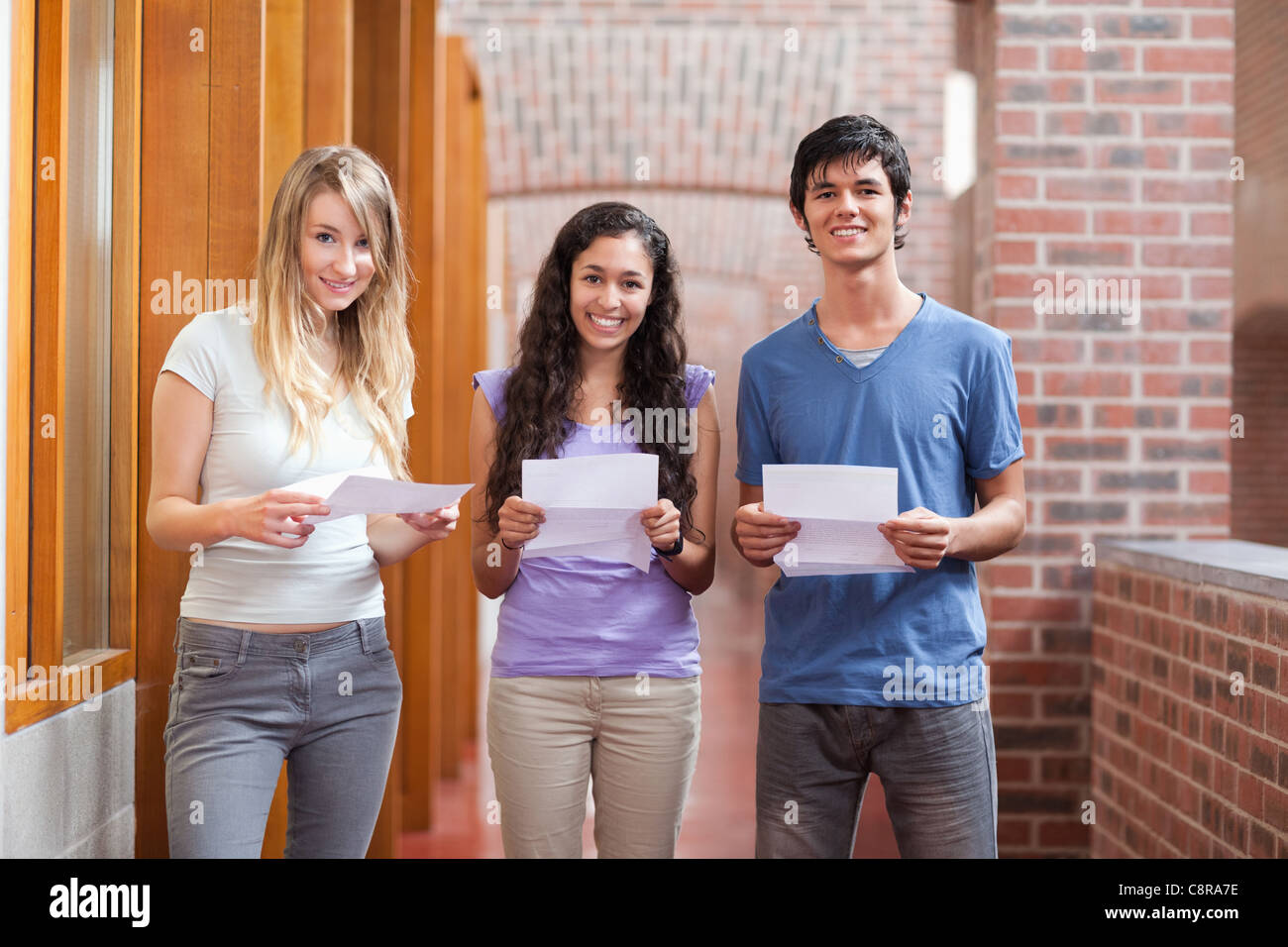 Smiling students holding a piece of paper Stock Photo - Alamy