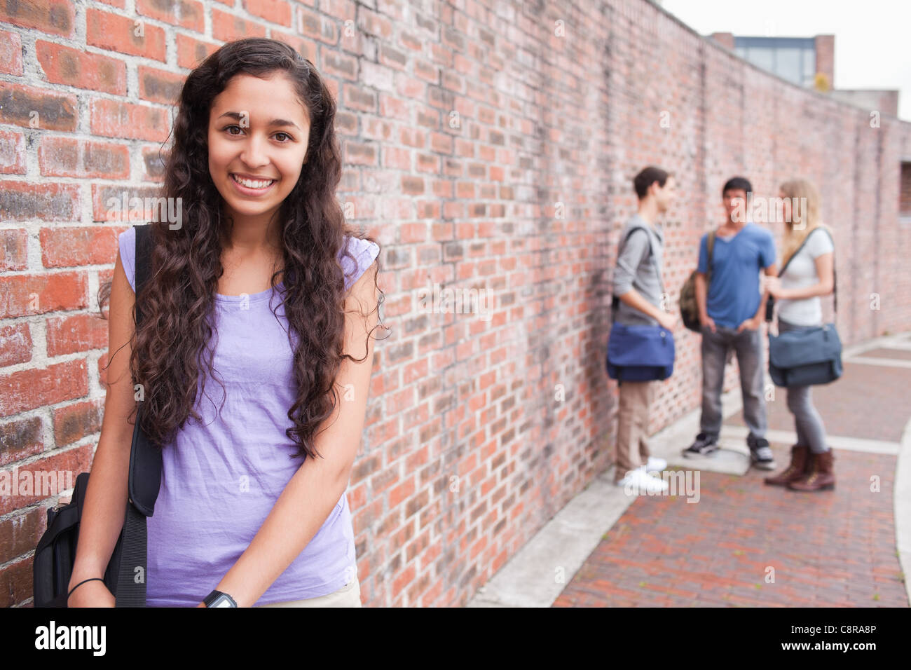 Smiling student posing while her friends are talking Stock Photo - Alamy