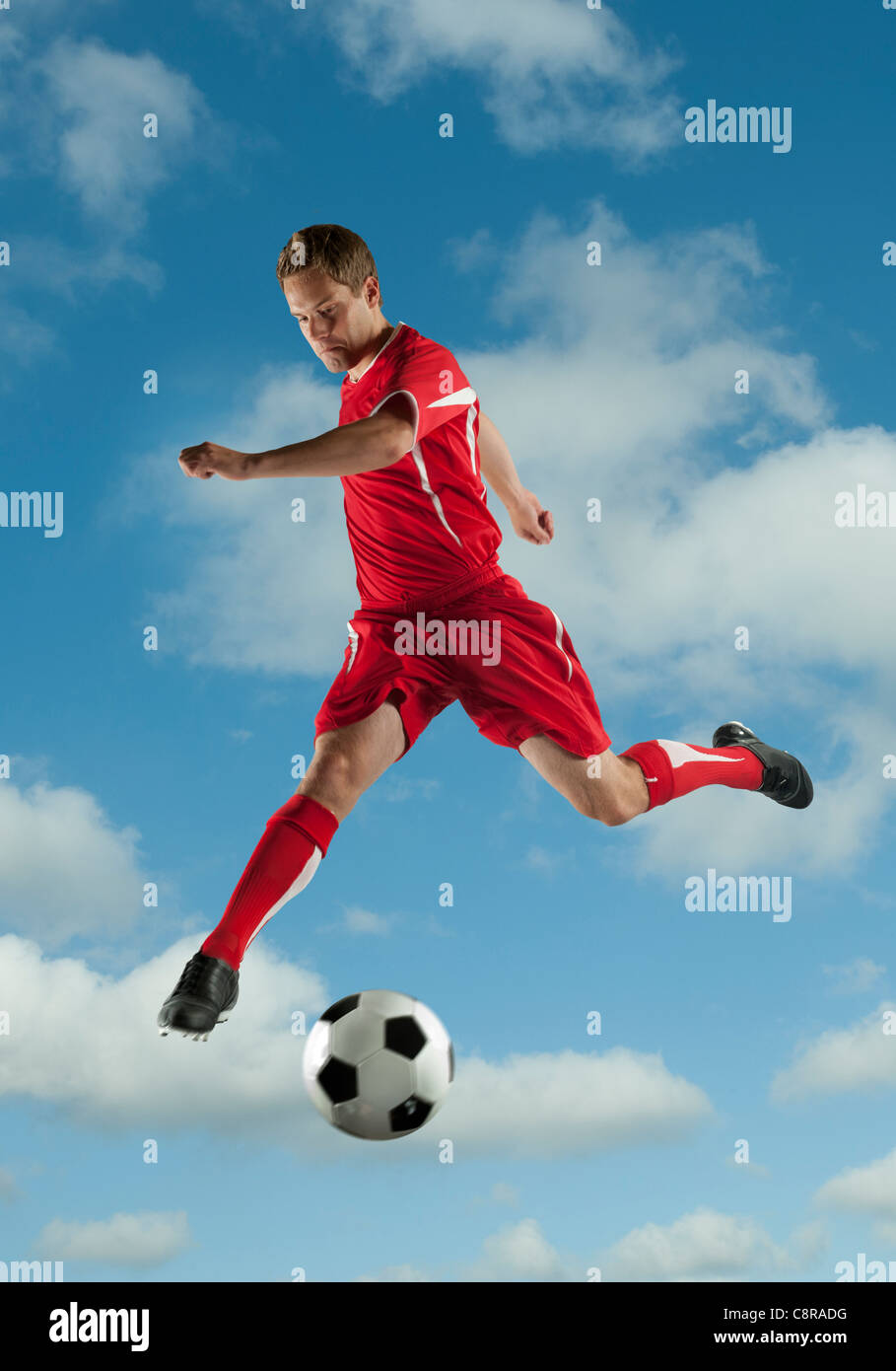 Soccer player jumping in mid-air kicking ball Stock Photo - Alamy