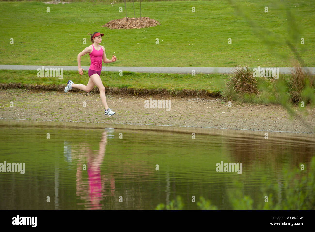 Mixed race woman running near pond Stock Photo - Alamy