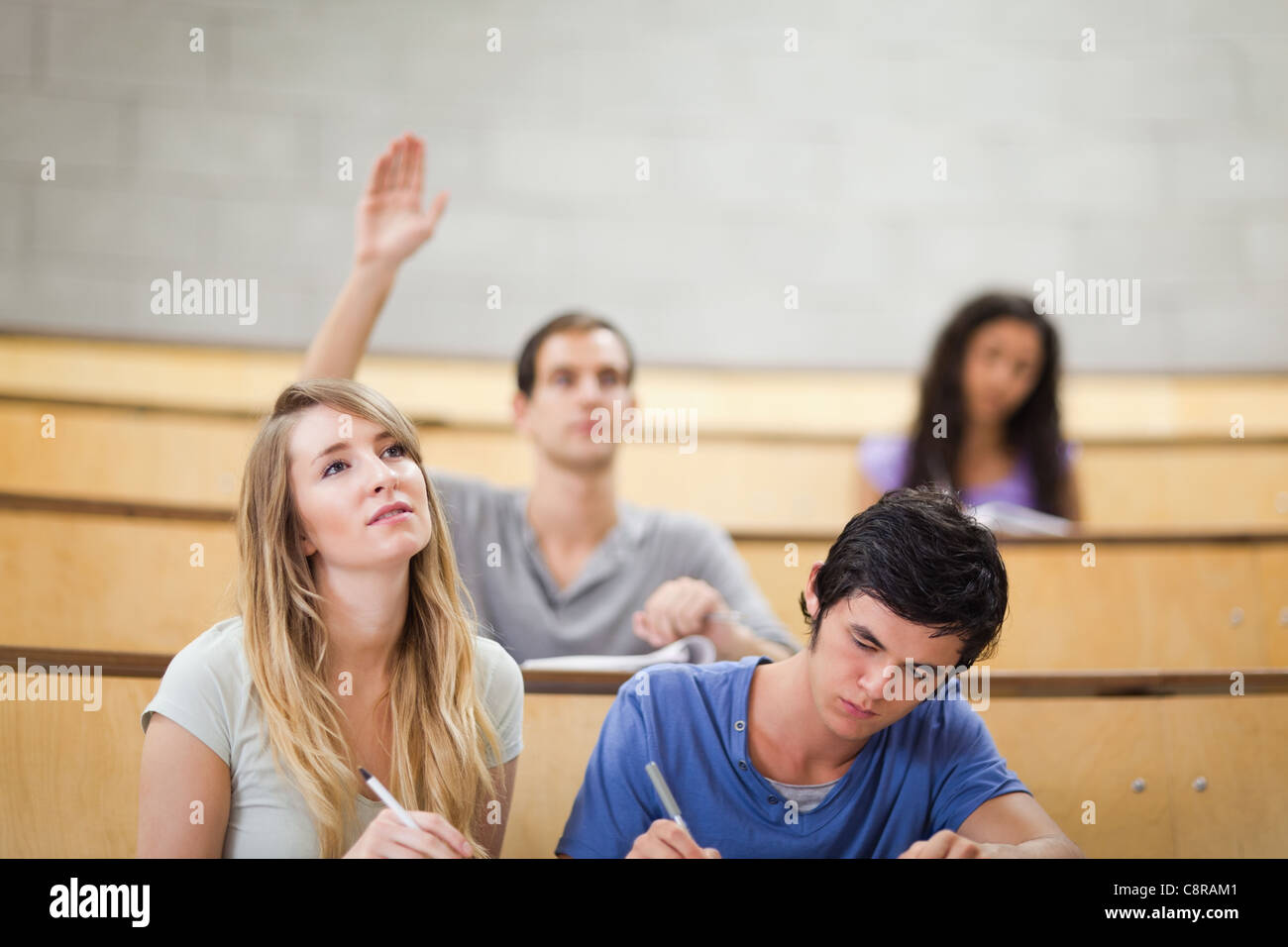 Students taking notes while their classmate is raising his hand Stock ...