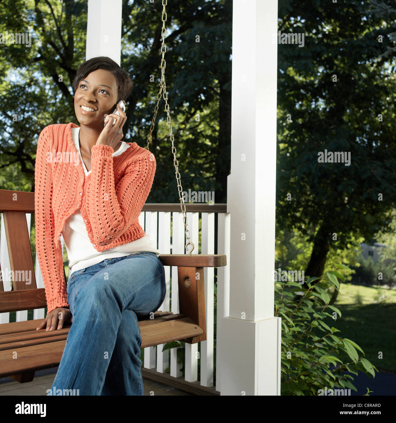 Mixed race woman using cell phone on porch Stock Photo - Alamy