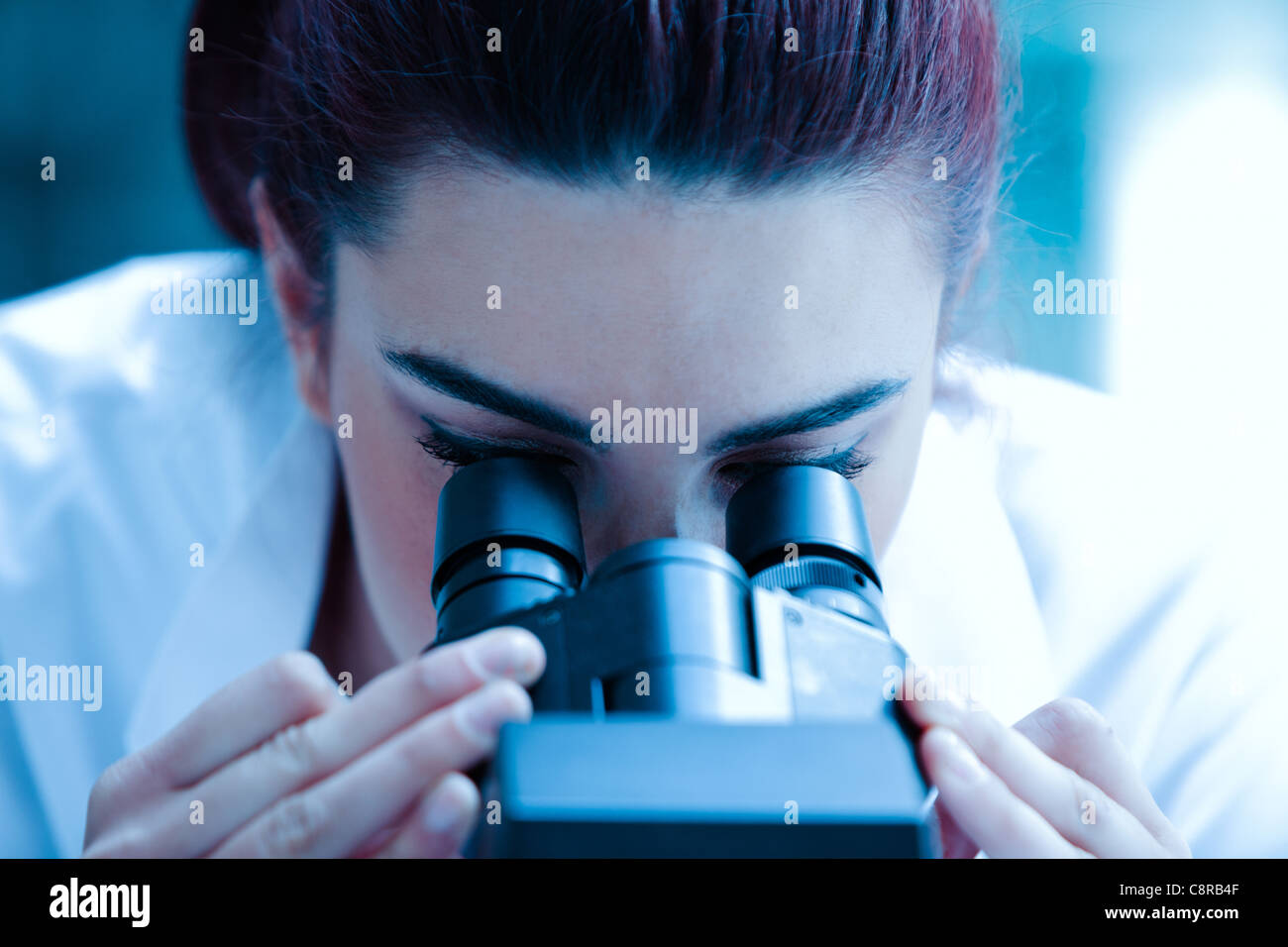 Young scientist looking through a microscope Stock Photo - Alamy