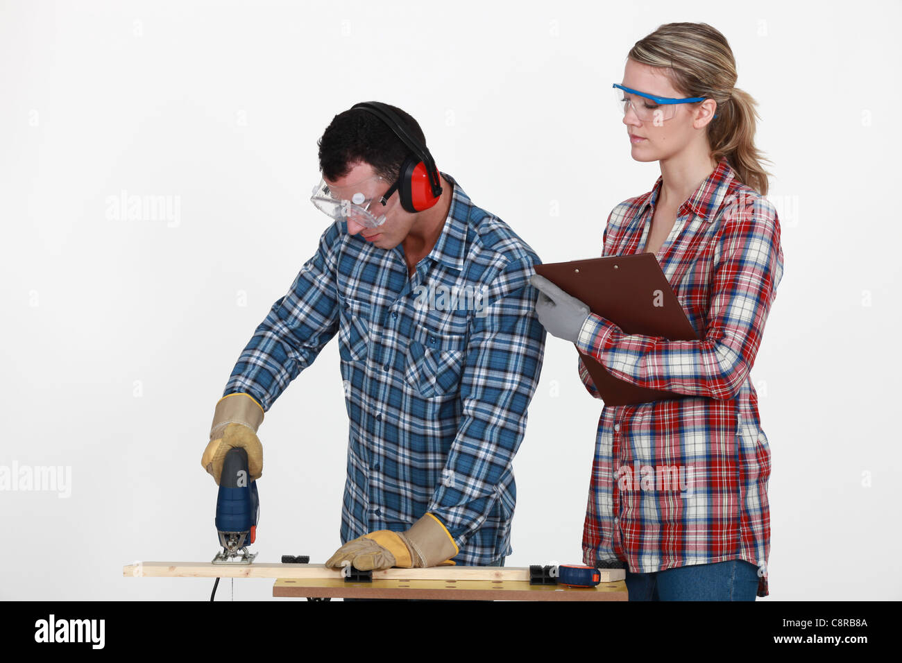 Man using band saw whilst woman supervises Stock Photo - Alamy