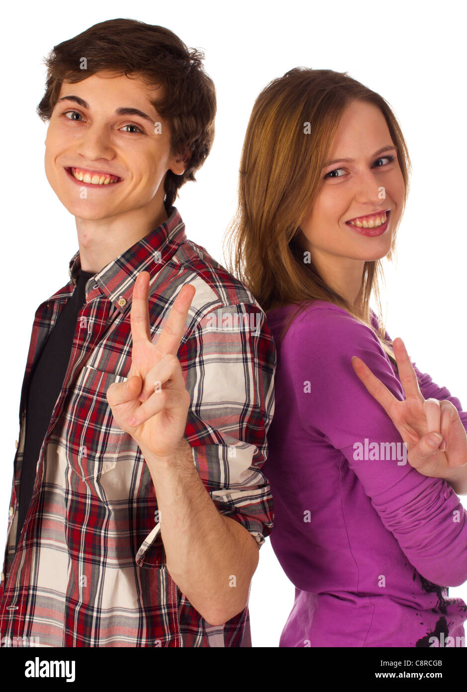 Young couple standing and showing victory gesture on white background ...