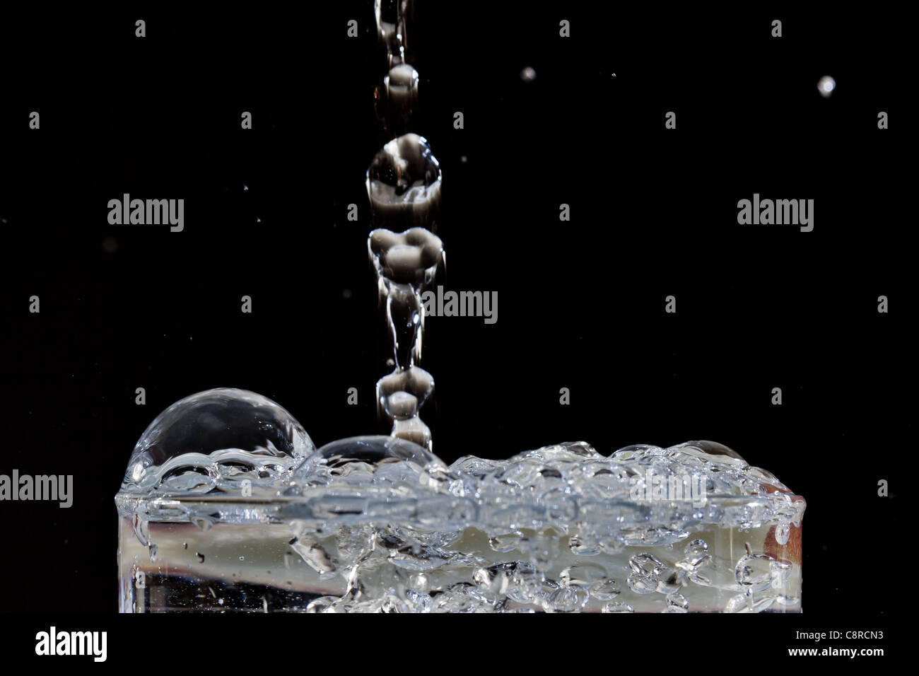 Water dripping into a glass of water forming bubbles Stock Photo - Alamy