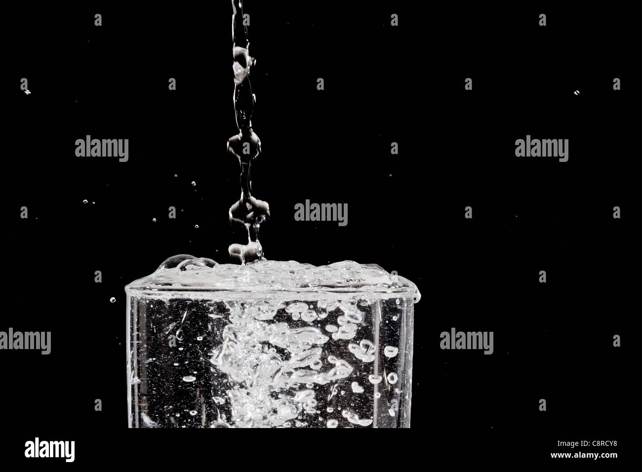 Water dripping into a glass of water forming bubbles Stock Photo - Alamy