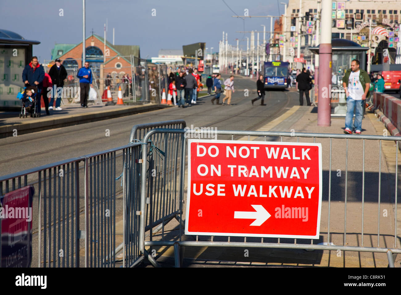 Red road sign stating, "Do not walk on tramway, use walkway", with ...