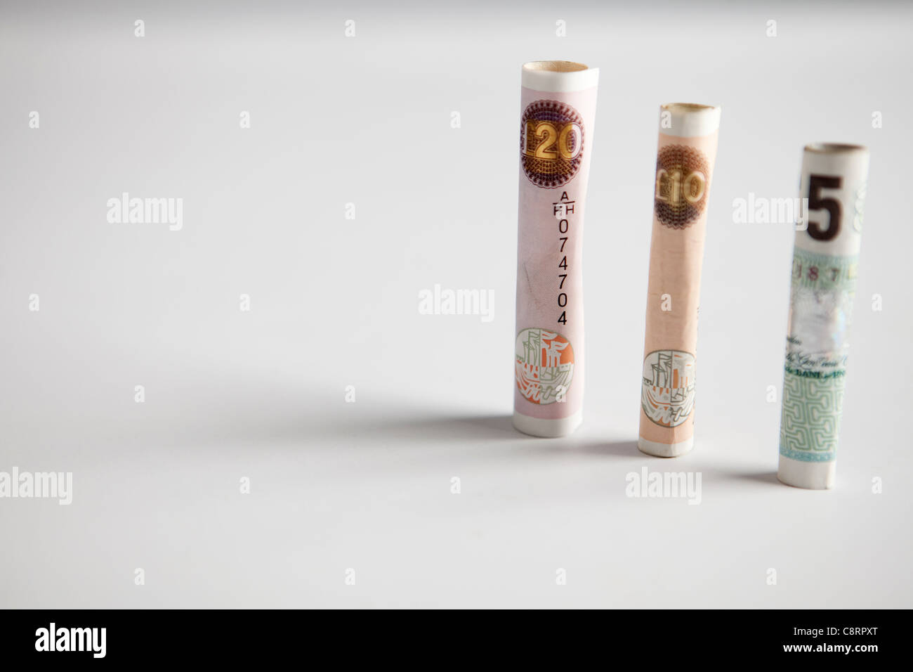 Three rolled up money notes against a white background Stock Photo - Alamy