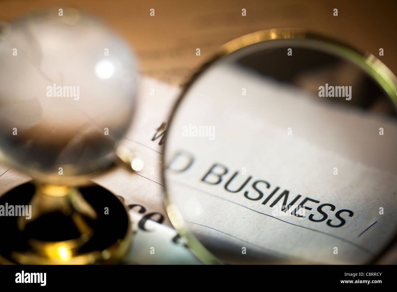 Close-up of paperweight on newspaper looking through magnifying glass ...
