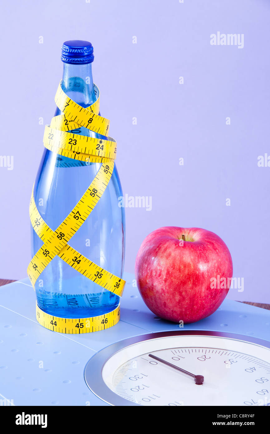 Bottle wrapped by measuring tape with apple on weighing scale Stock ...