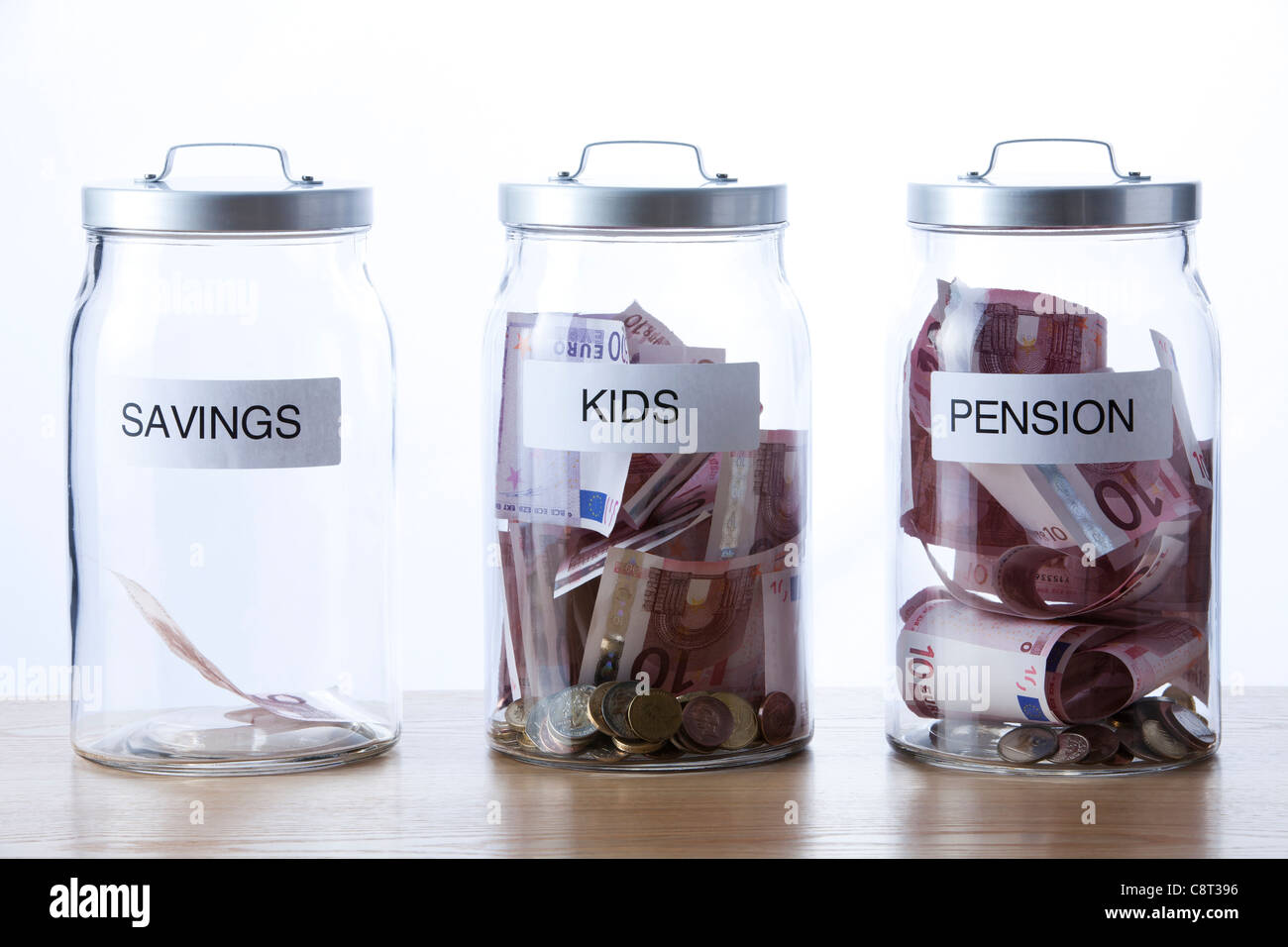 Three glass jar with label filled with money Stock Photo - Alamy
