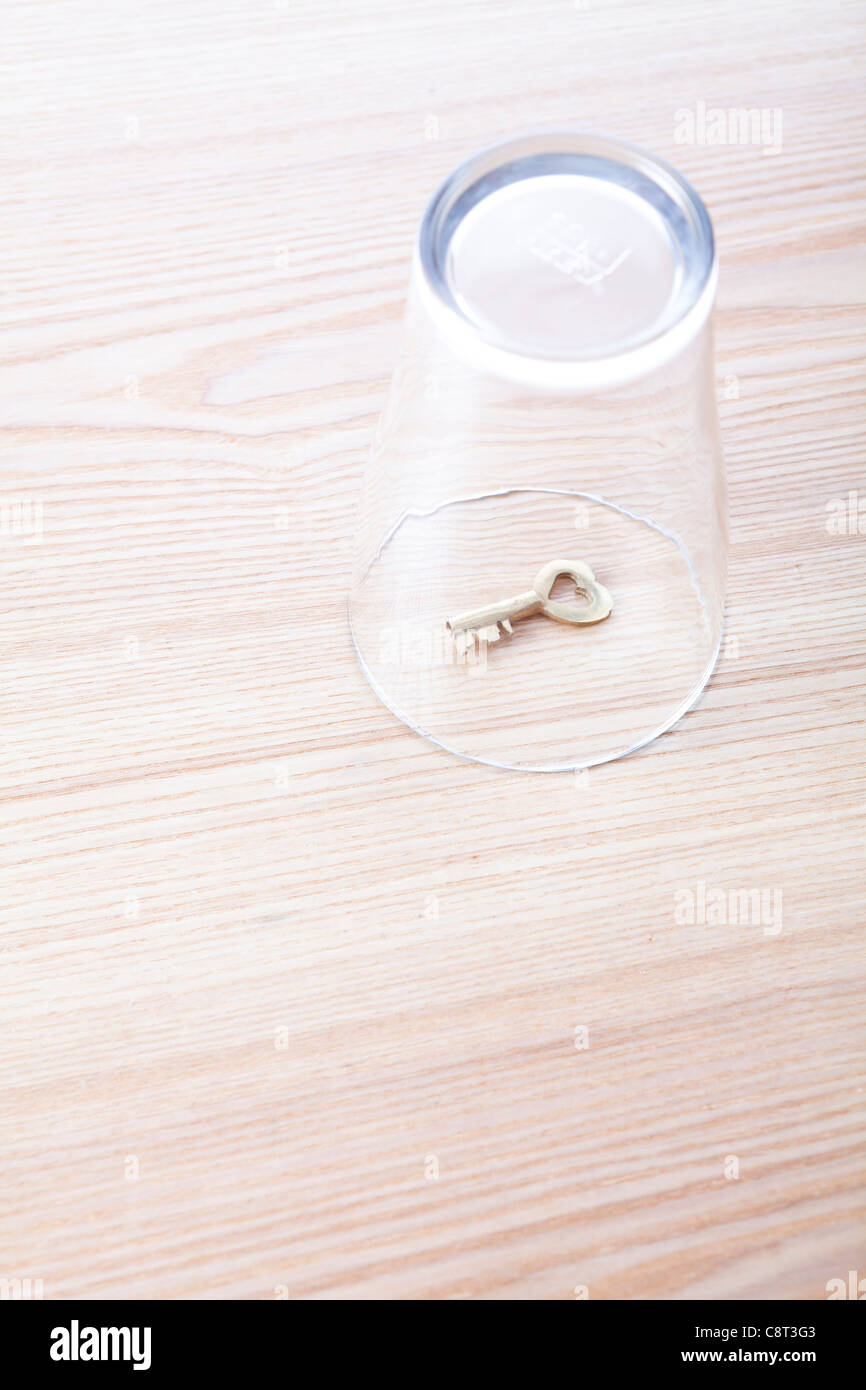 Glass upside down with key inside it, high angle view Stock Photo - Alamy