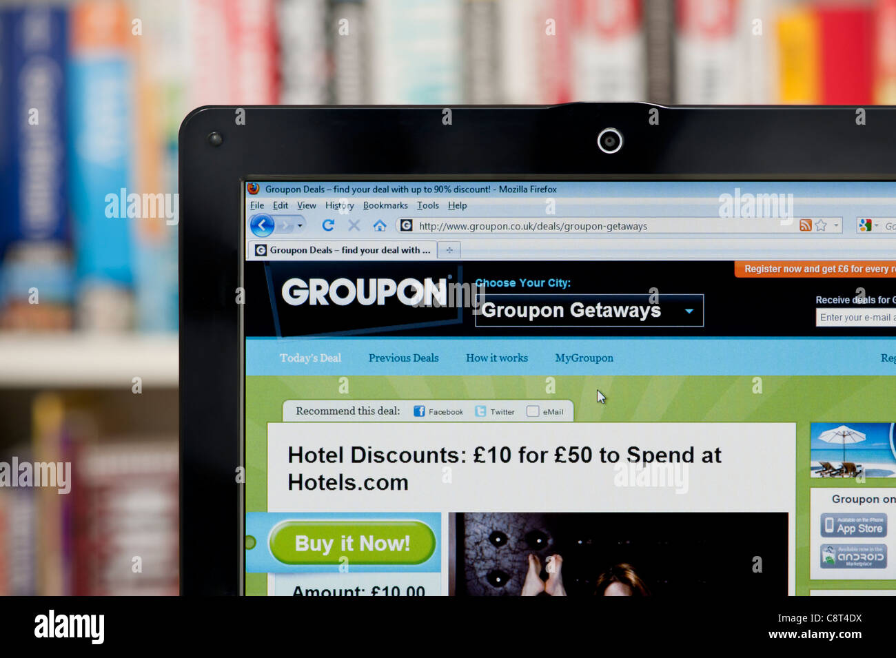 The Groupon website shot against a bookcase background (Editorial use ...
