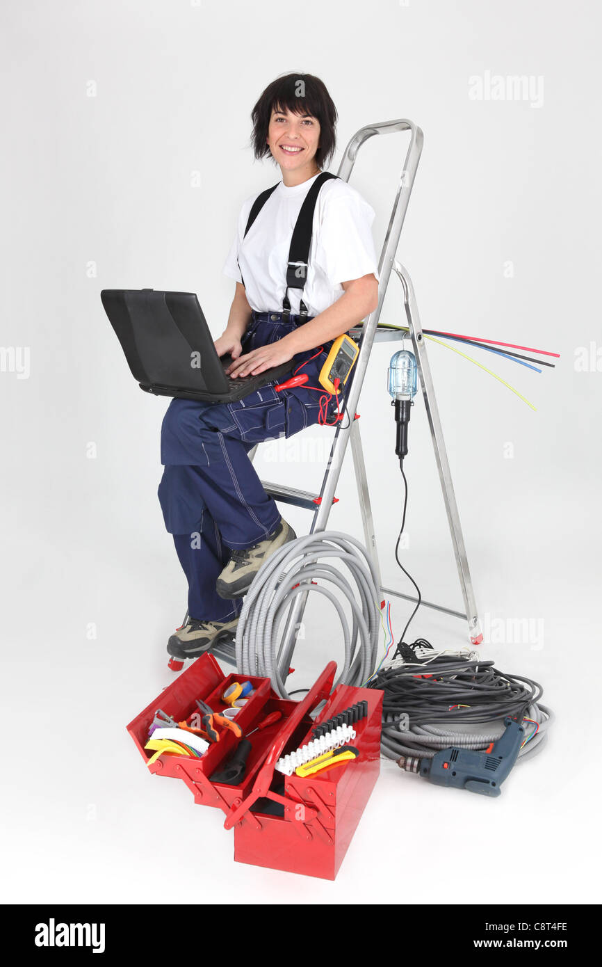 Woman electrician sitting on a ladder with laptop Stock Photo - Alamy