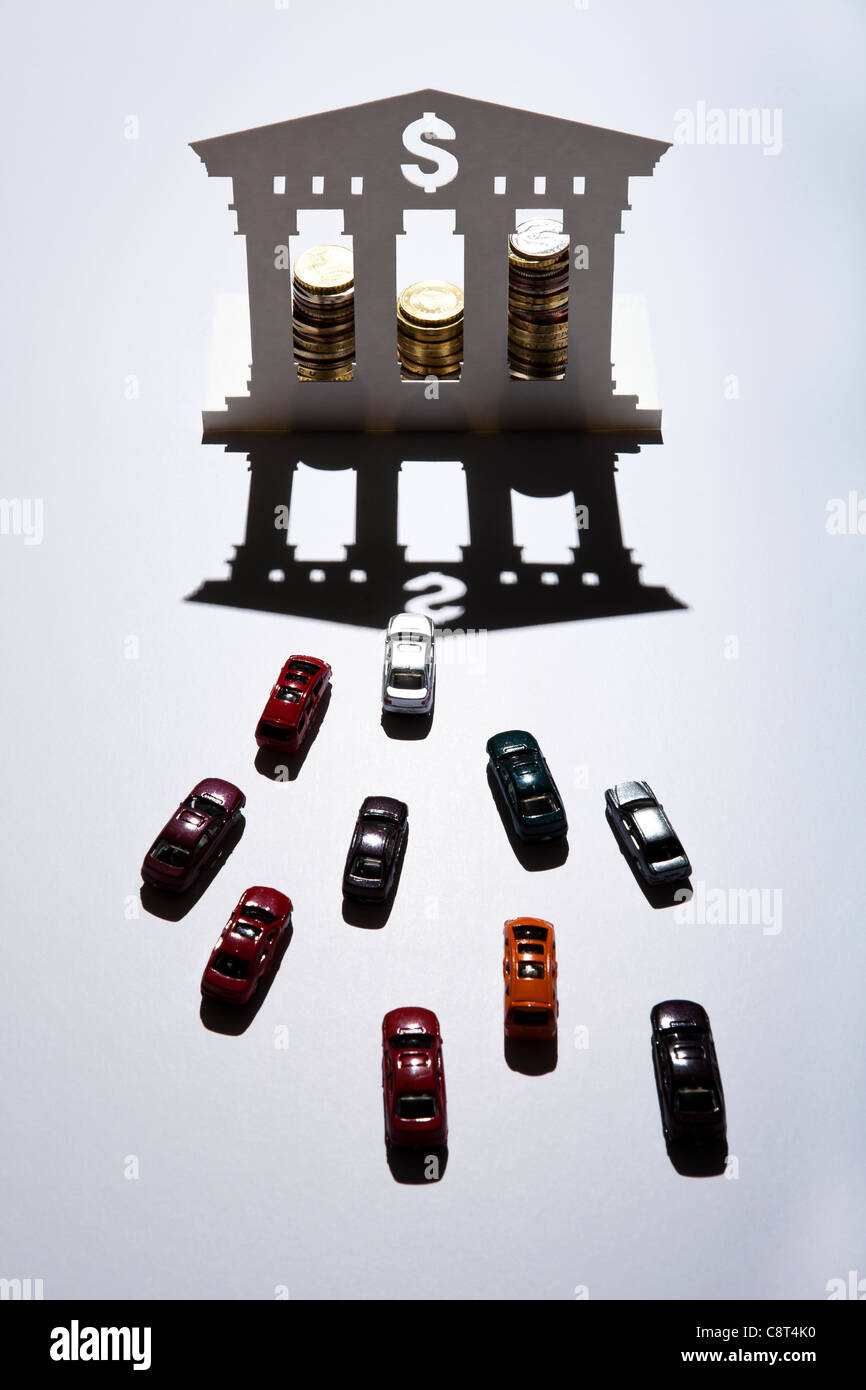 High angle view of toy cars in front of model of bank with dollar sign ...