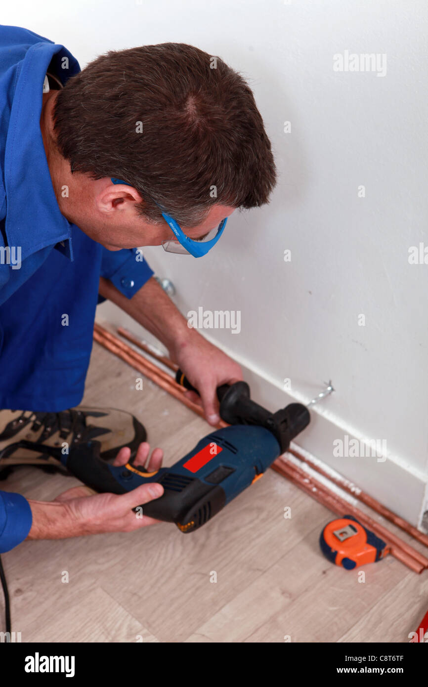 Plumber drilling a wall Stock Photo - Alamy