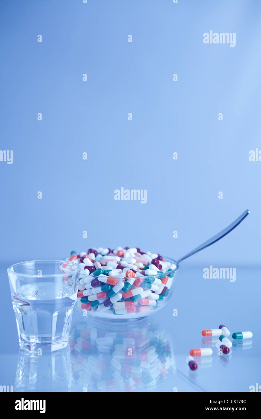 Bowl full of pills along with glass of water Stock Photo - Alamy