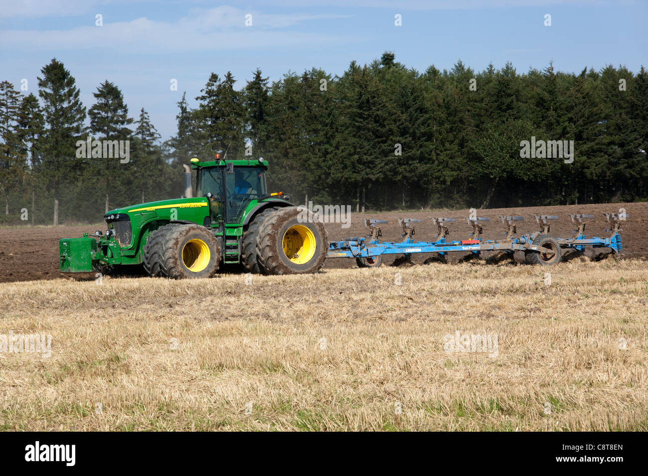 Big tractor pull a plough on a late summer stubble field. Southern ...