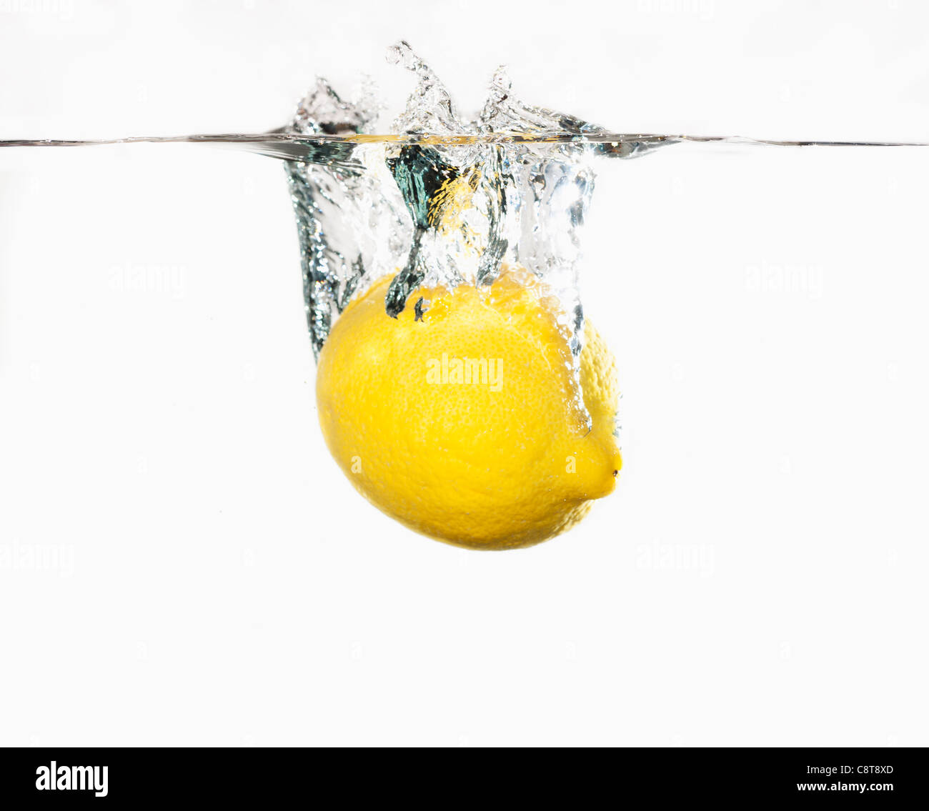 Studio shot of lemon splashing into water Stock Photo - Alamy
