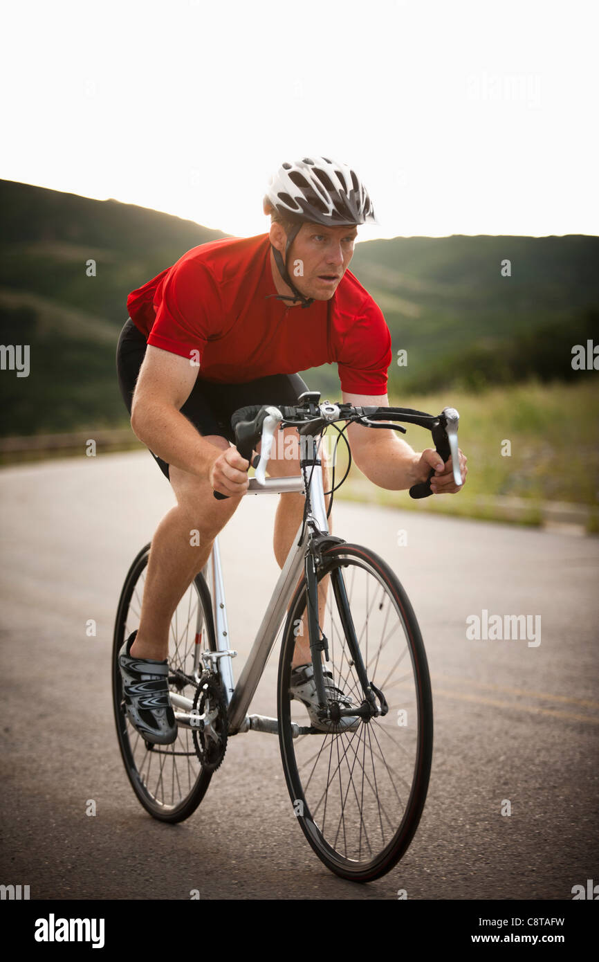Caucasian man riding bicycle on remote road Stock Photo - Alamy