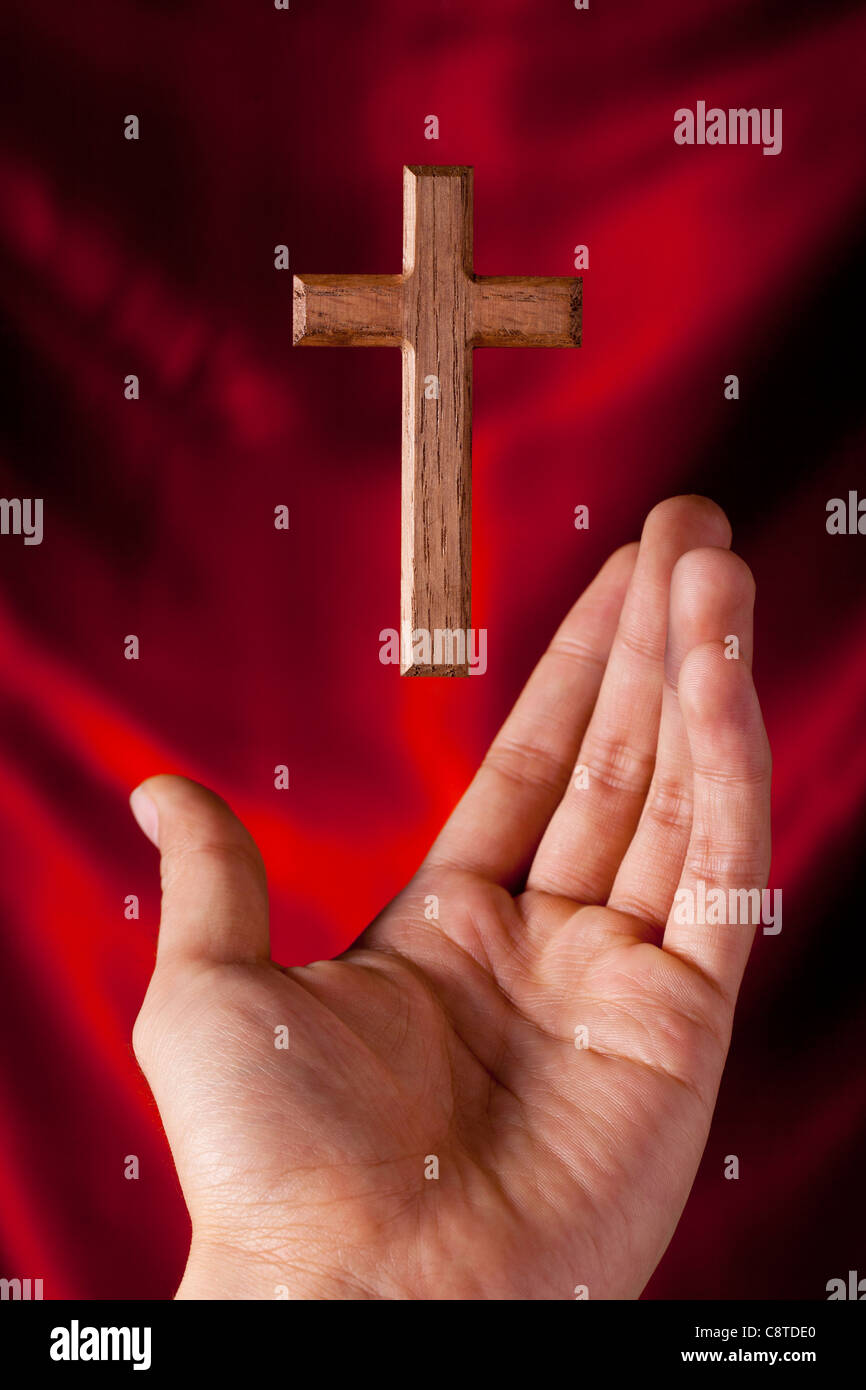 Wooden cross and human hand over dark red background Stock Photo - Alamy