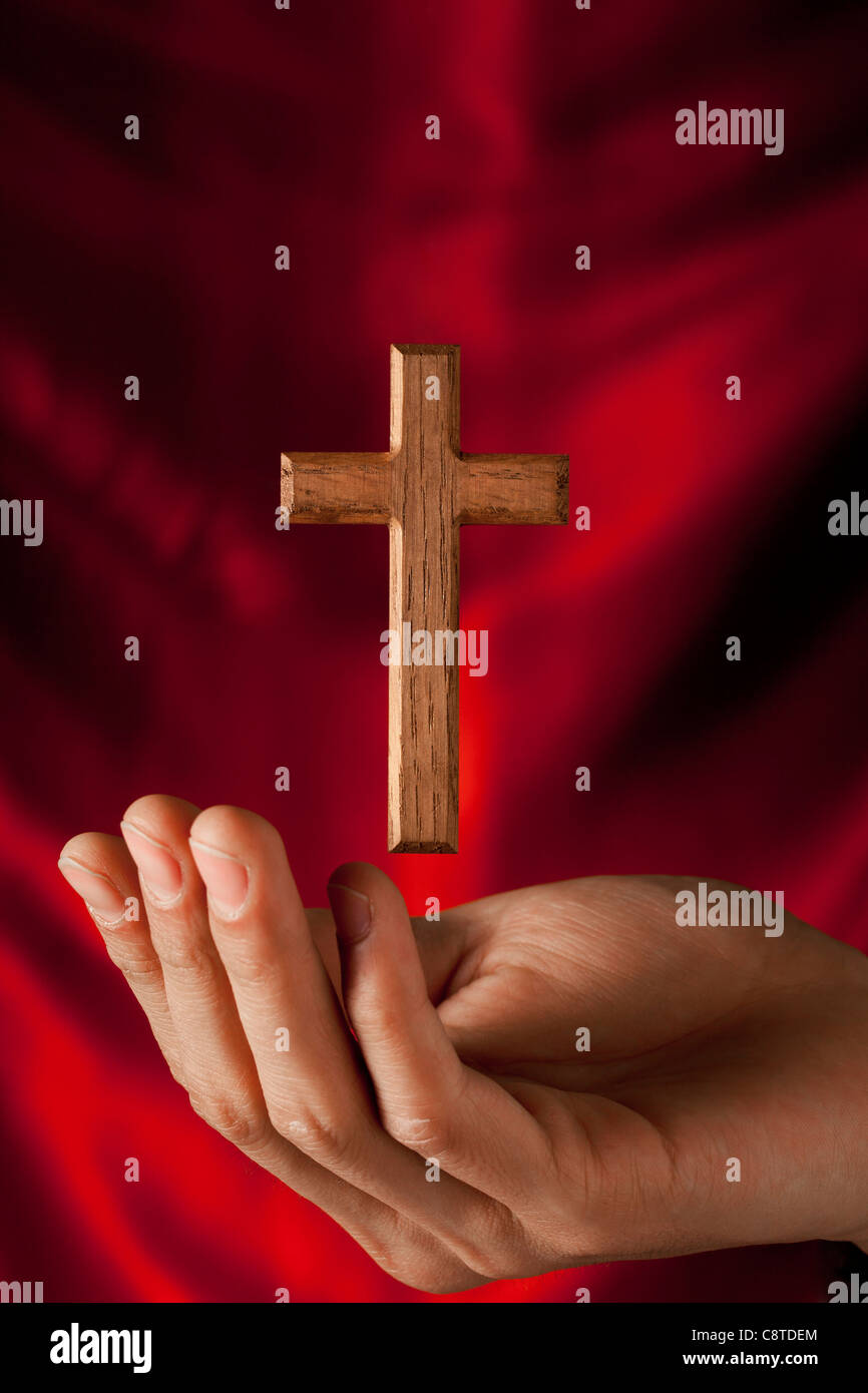 Wooden cross and human hand over dark red background Stock Photo - Alamy
