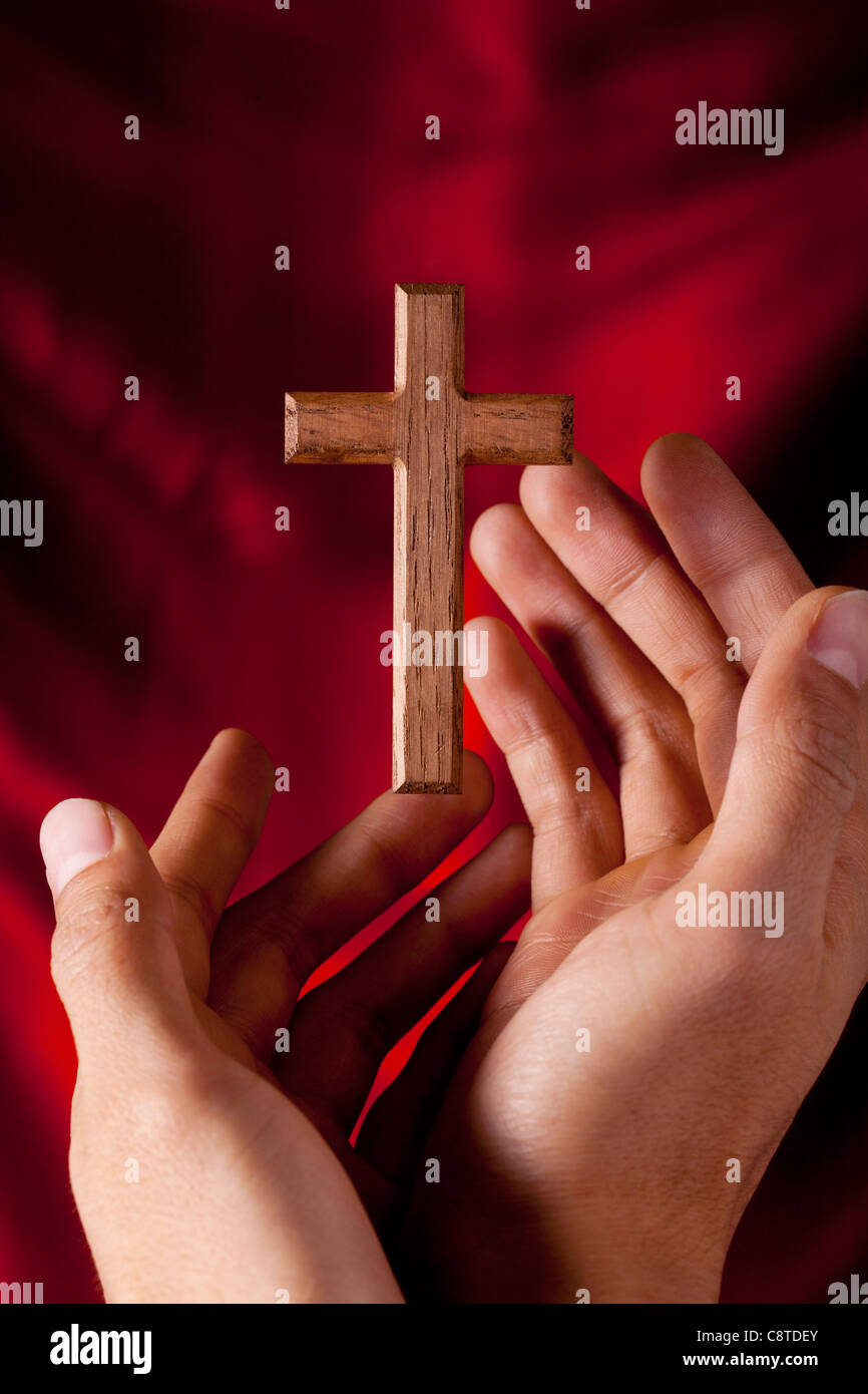 Wooden cross and human hands over dark red background Stock Photo - Alamy