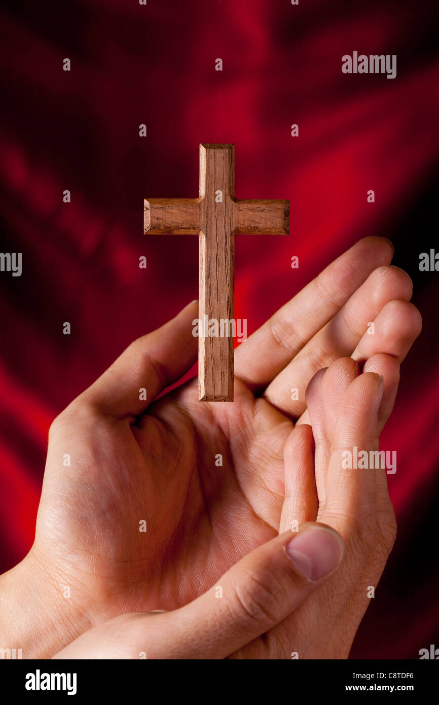 Wooden cross and human hands over dark red background Stock Photo - Alamy