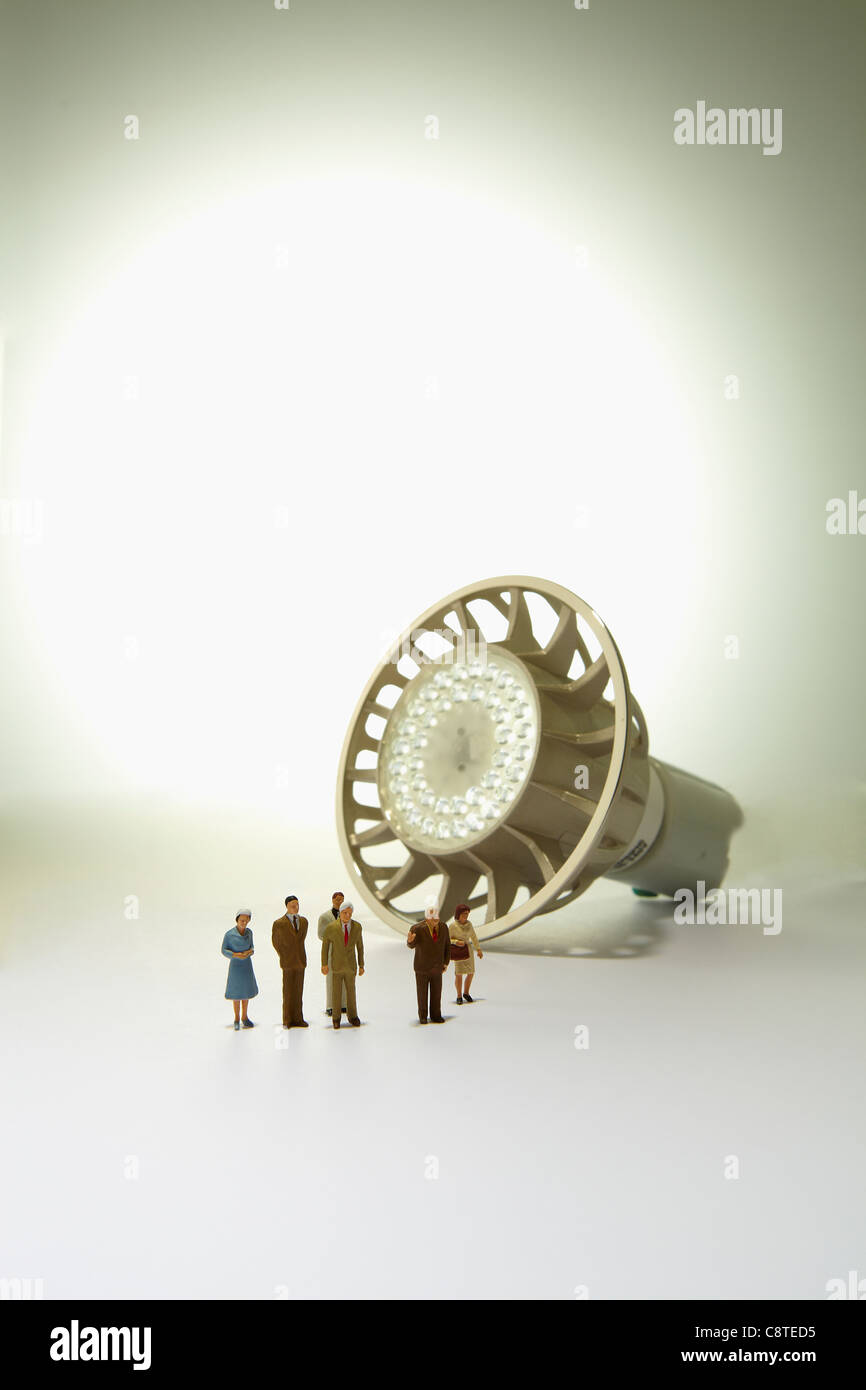 Small figurines standing in front of LED bulb Stock Photo - Alamy