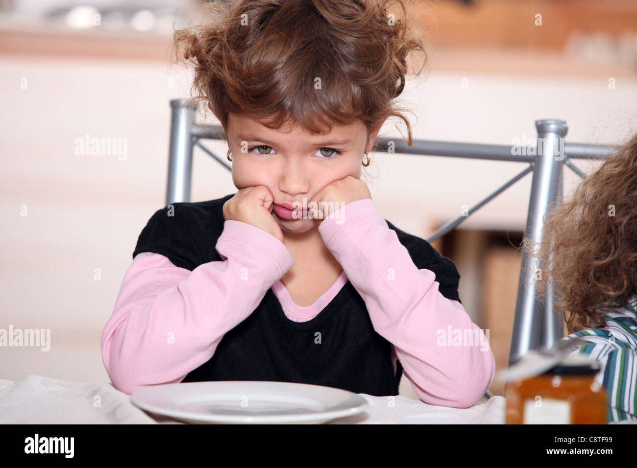 Sulky girl sitting at the breakfast table Stock Photo - Alamy