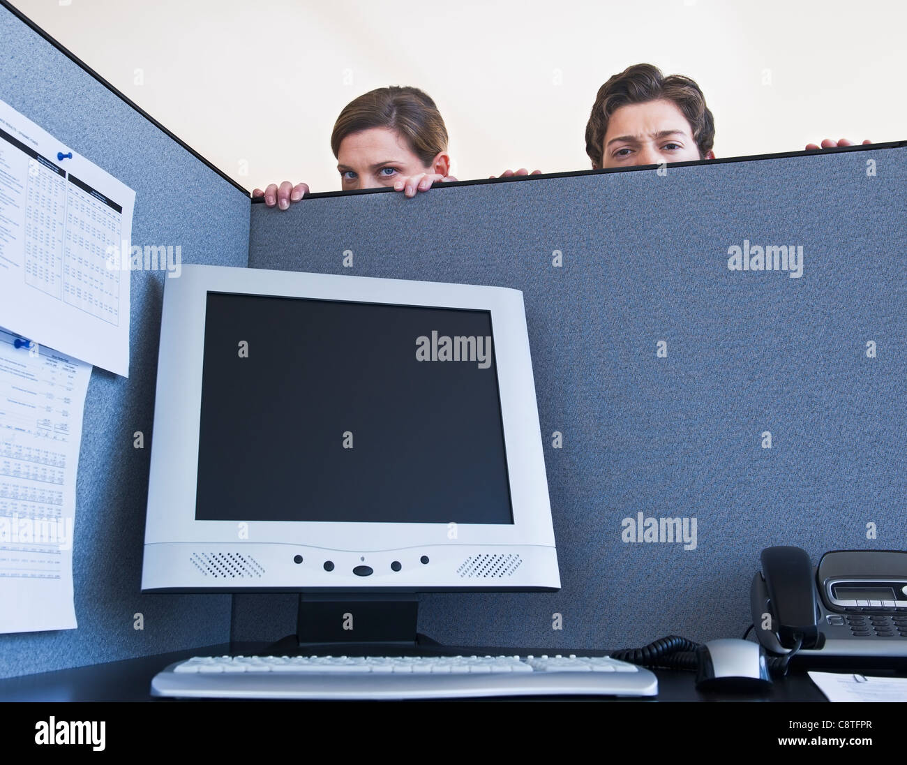 USA, New Jersey, Jersey City, Office workers hiding behind cubicle wall ...