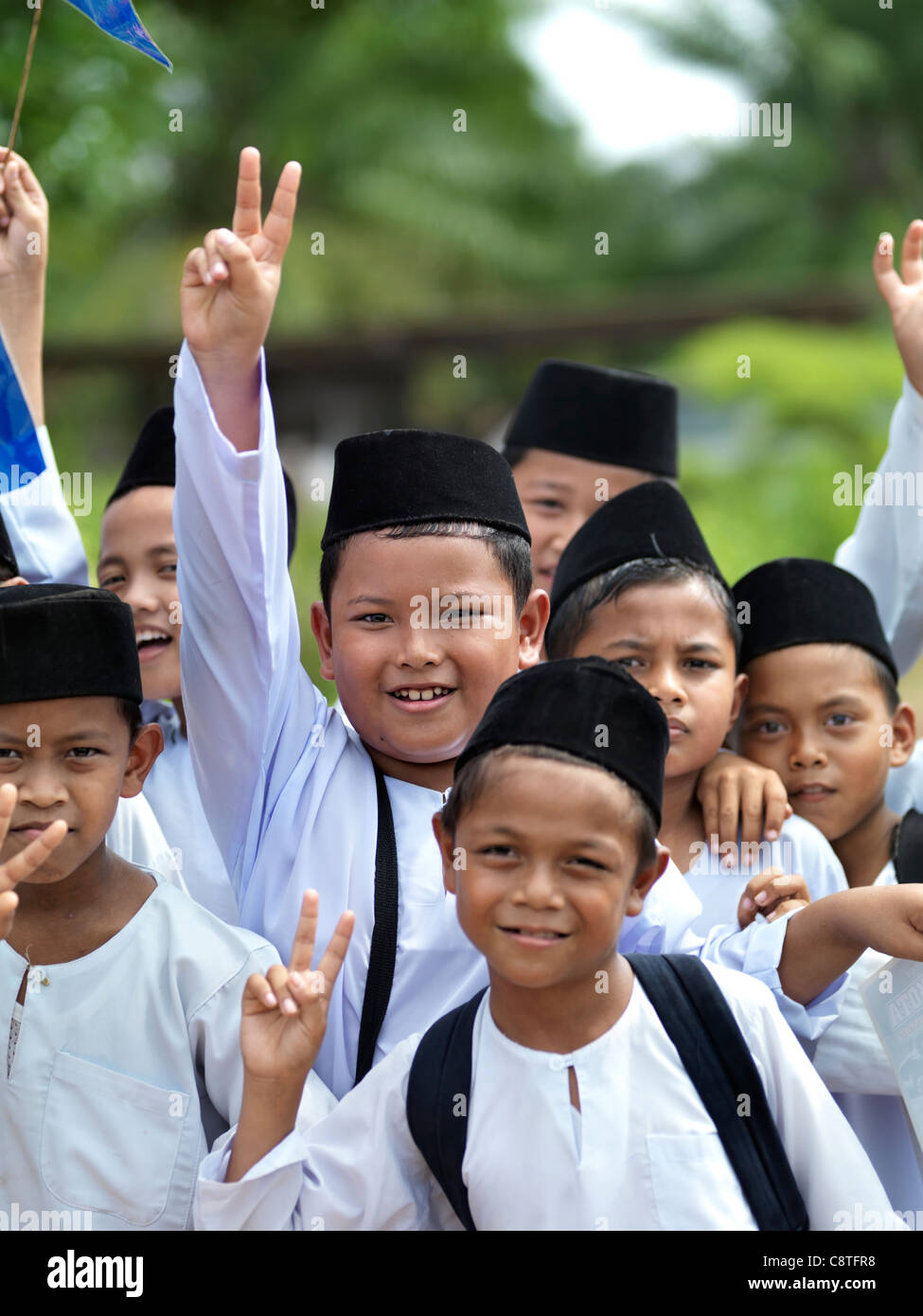 A crowd of young Muslim children posing happily with the peace sign ...